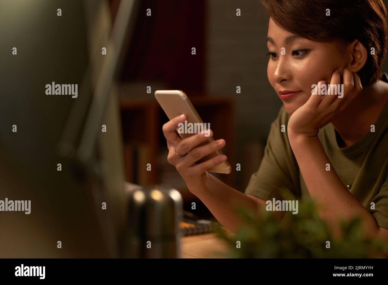 Pretty bored Asian woman reading something on smartphone Stock Photo ...