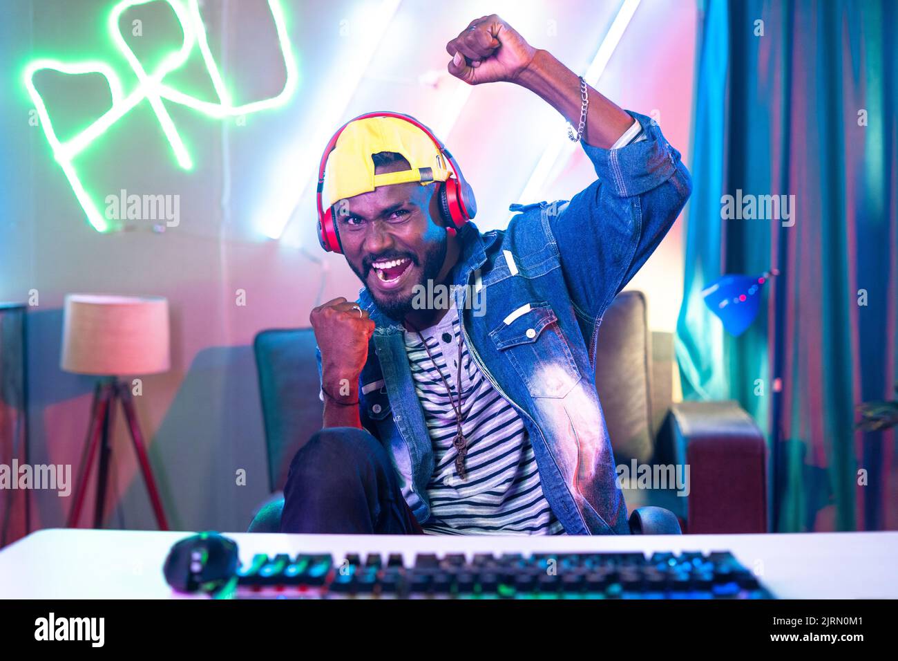 Excited gamer with headset celebrating victory by shouting while ...