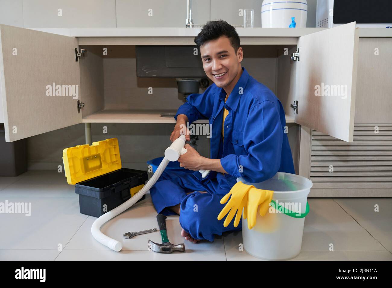 Portrait of smiling Vietnamese plumber repairing sink Stock Photo - Alamy