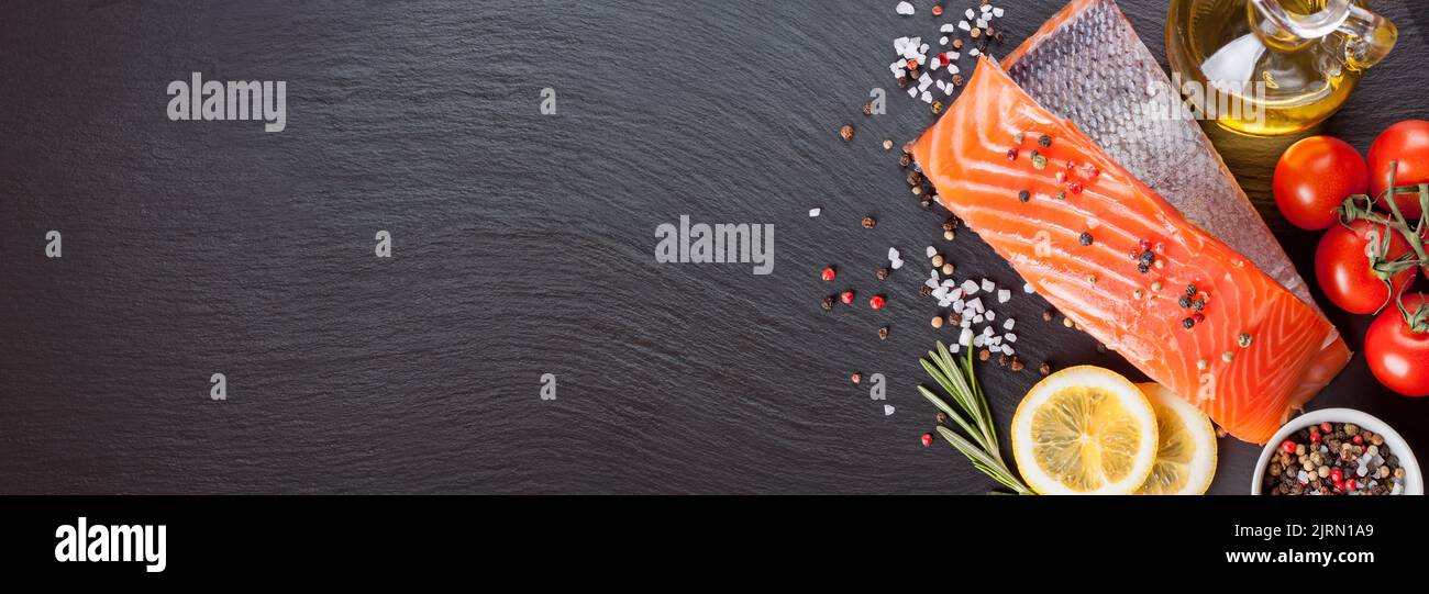 Raw salmon fillet and ingredients for cooking on a dark slate ...