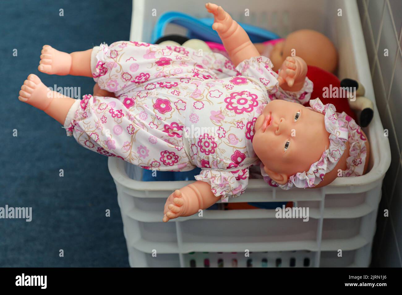 White plastic box on an oil blue floor with several plastic dolls ...