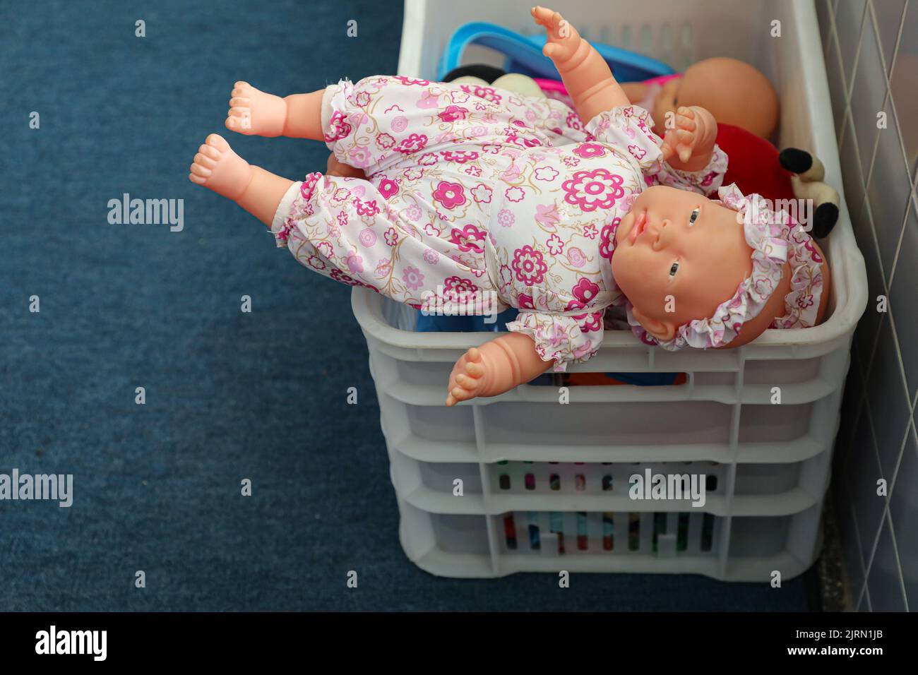 White plastic box on an oil blue floor with several plastic dolls ...