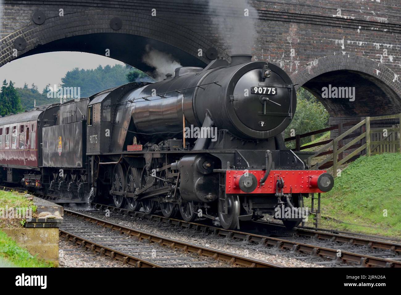 large black steam train passing under a bridge Stock Photo - Alamy