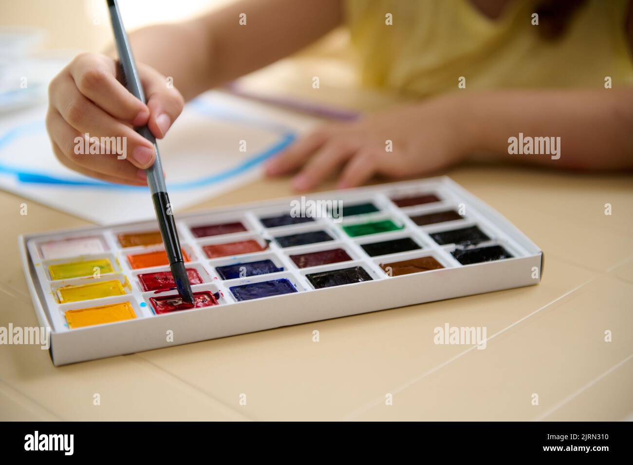 Details: child hand holding brush and mixing paints on colorful ...