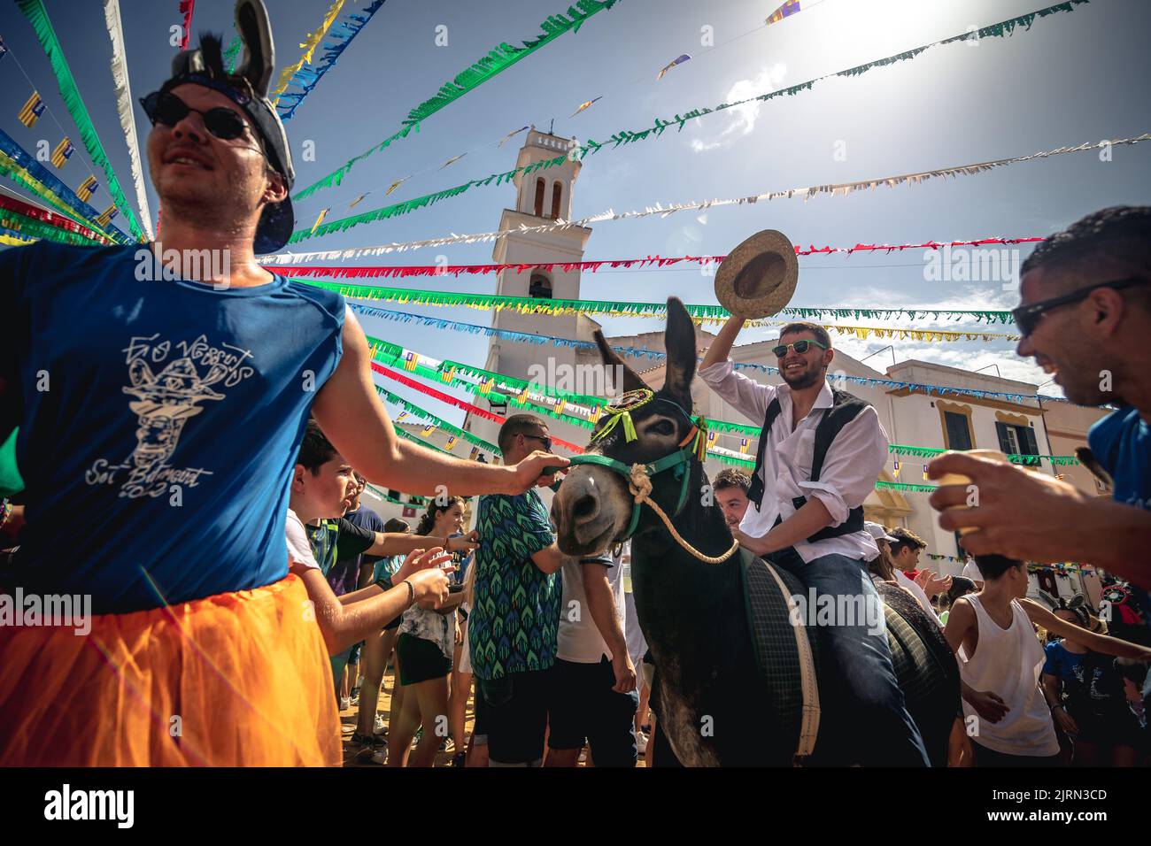 Ferreries, Spain. 25th Aug, 2022. A costumed reveler rides on a donkey ...