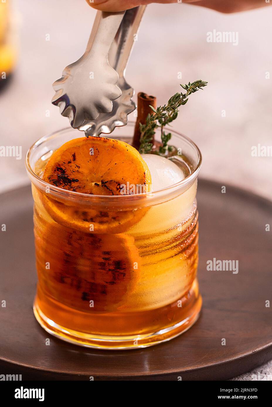 Whiskey sour cocktail with tangerine slices and ice cubes decorated ...