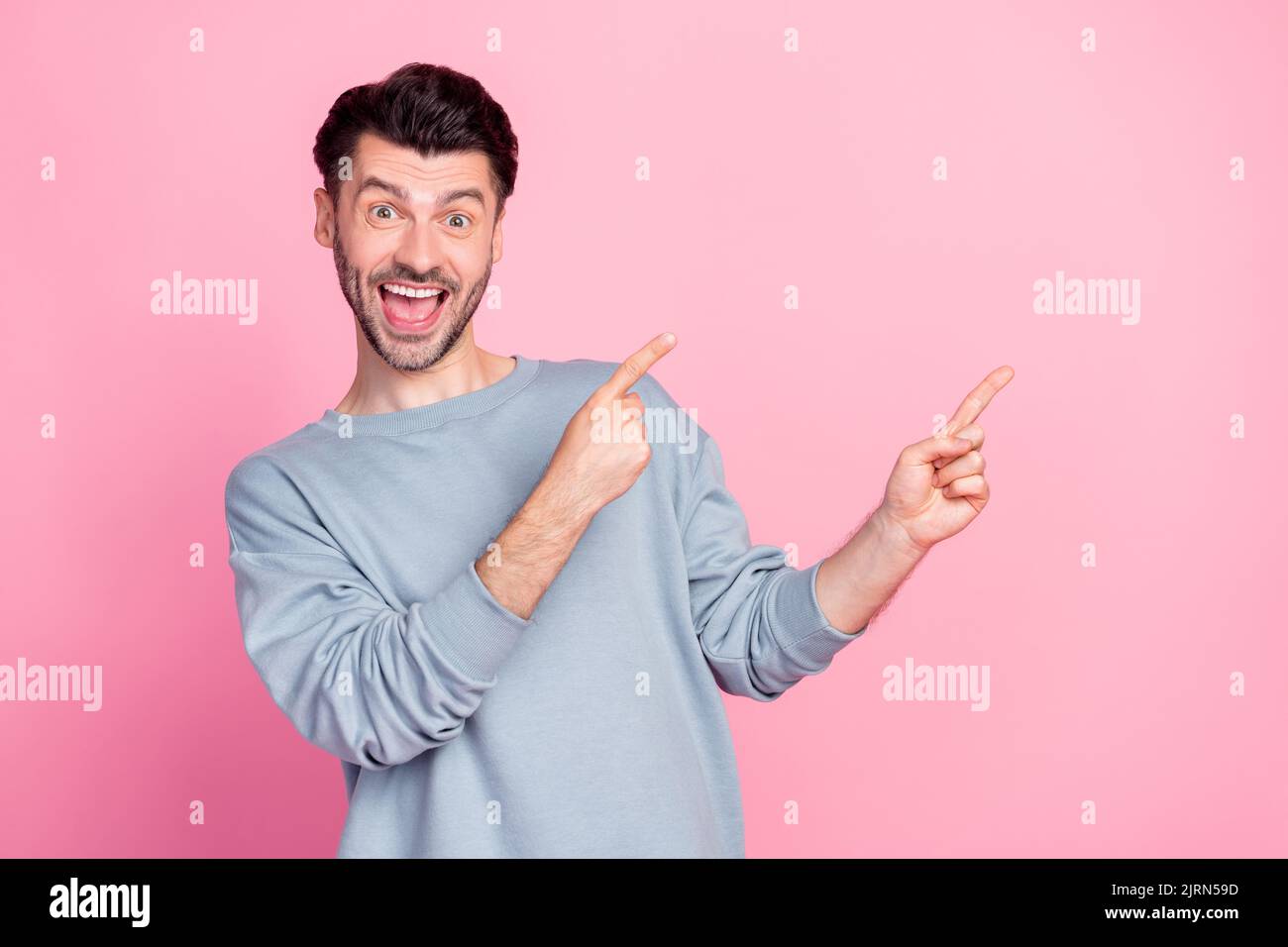 Photo of astonished cheerful man indicate fingers empty space isolated ...