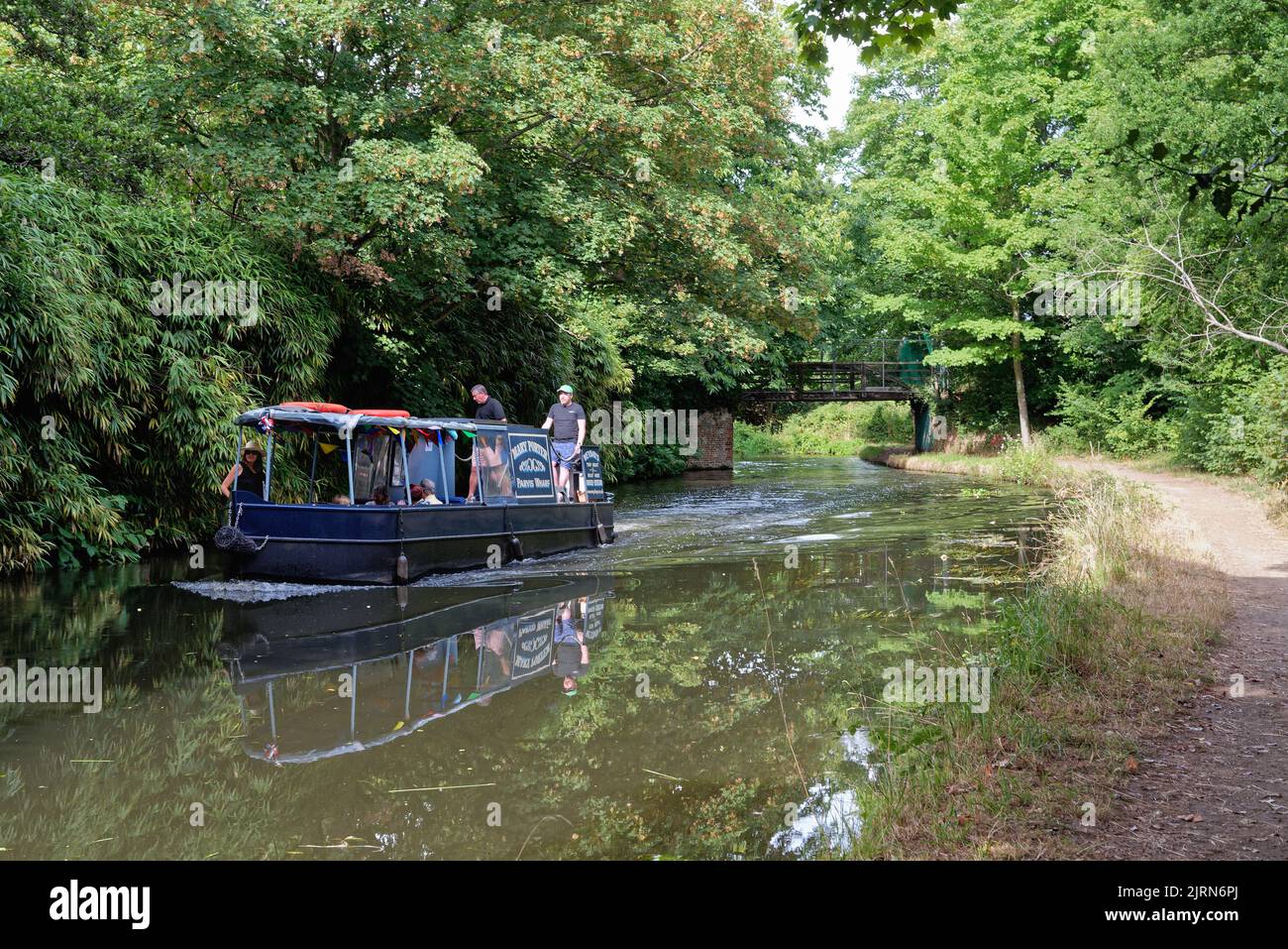 A narrow boat cruising on the River Wey navigation canal on a summers ...