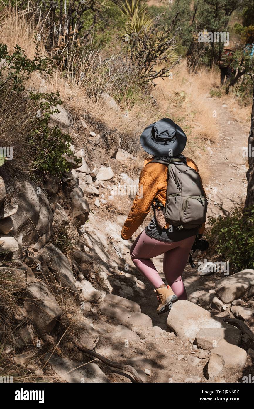 A vertical shot of a woman walking down a hill with a messy road full ...
