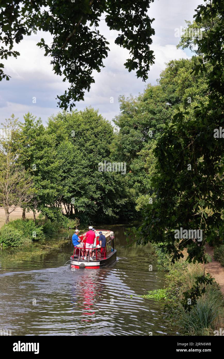 A narrow boat cruising on the River Wey navigation canal on a summers ...