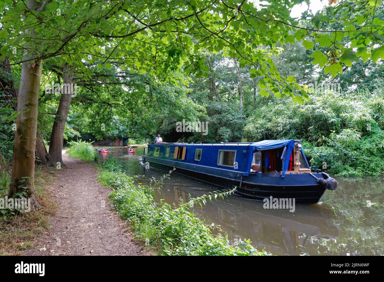 A narrow boat cruising on the River Wey navigation canal on a summers ...