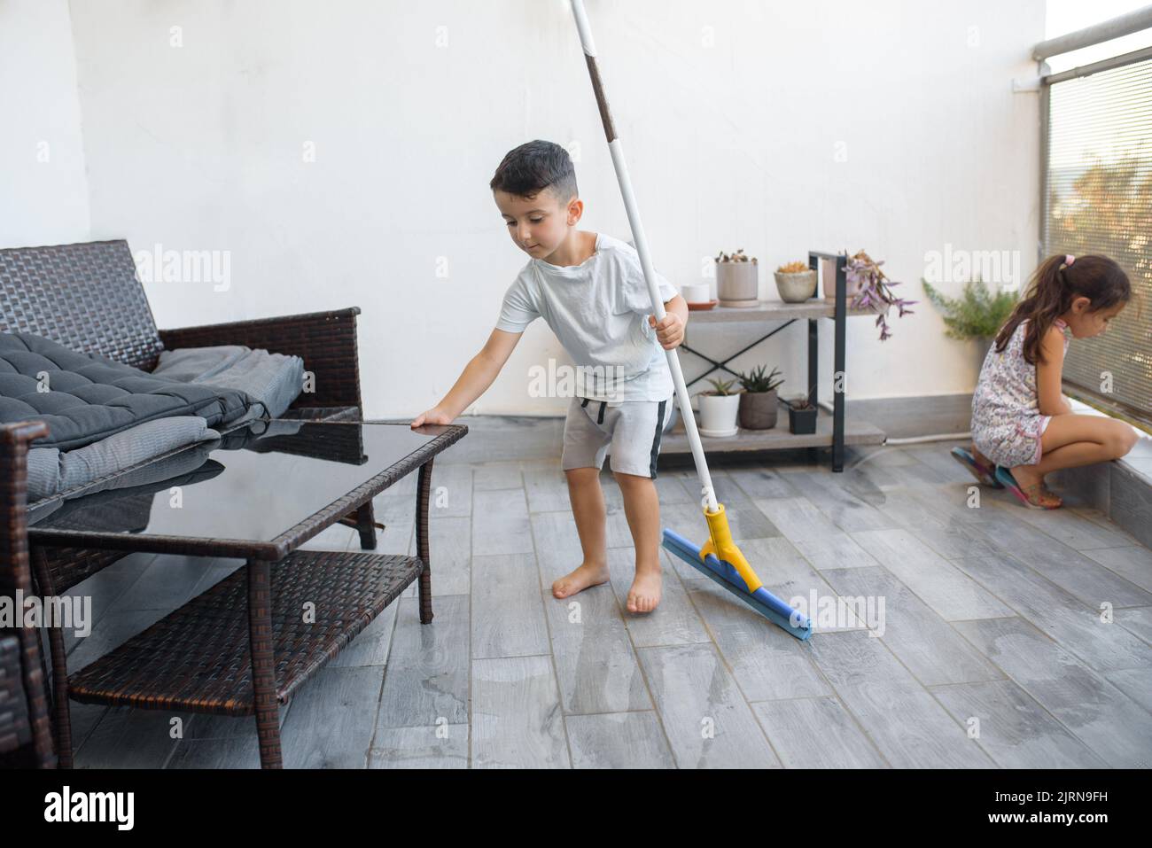 Funny young child cleaning floor at home. Boy washing floor with ...