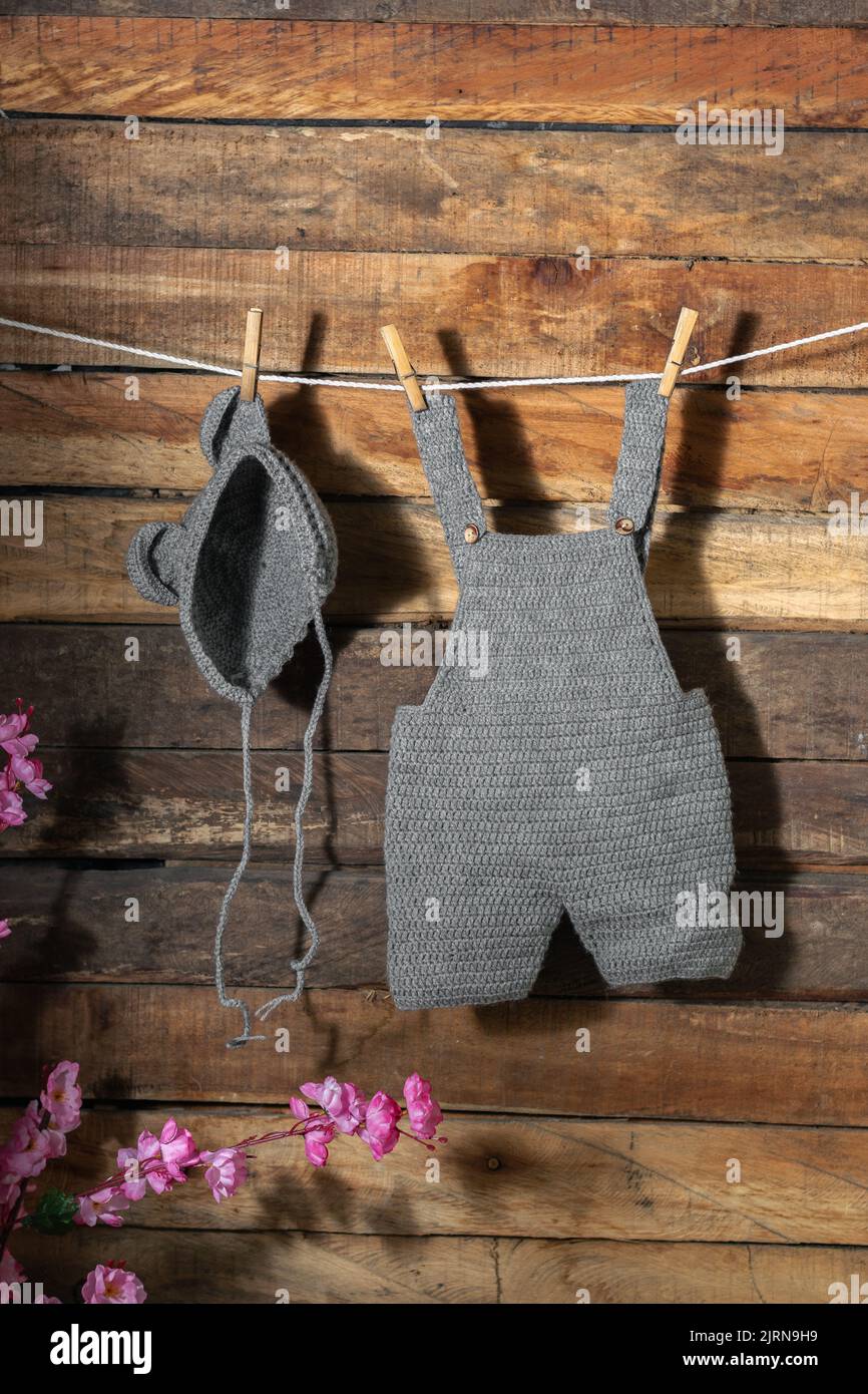 baby clothes hanging from a clothesline rope tied with wooden hooks ...