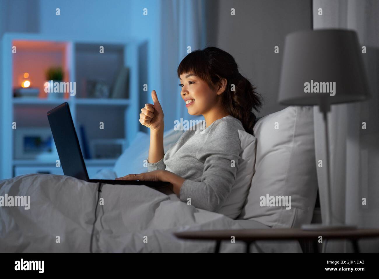 woman having video call on laptop in bed at night Stock Photo - Alamy