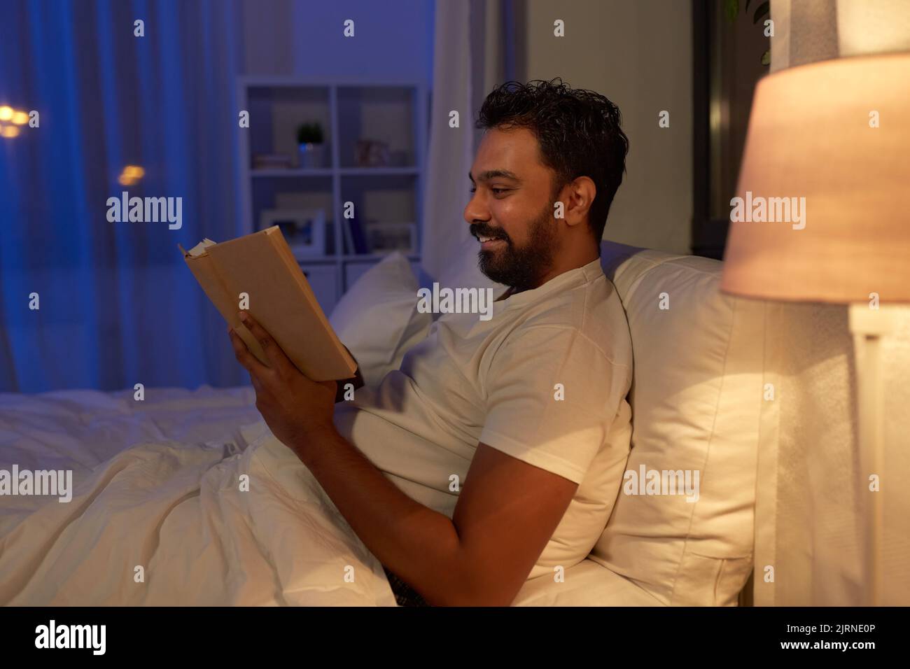 happy indian man reading book in bed at night Stock Photo - Alamy