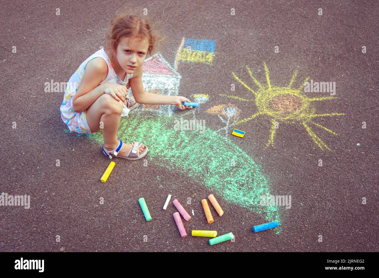 Ukrainian girl child draws children's drawings with chalk on the ...