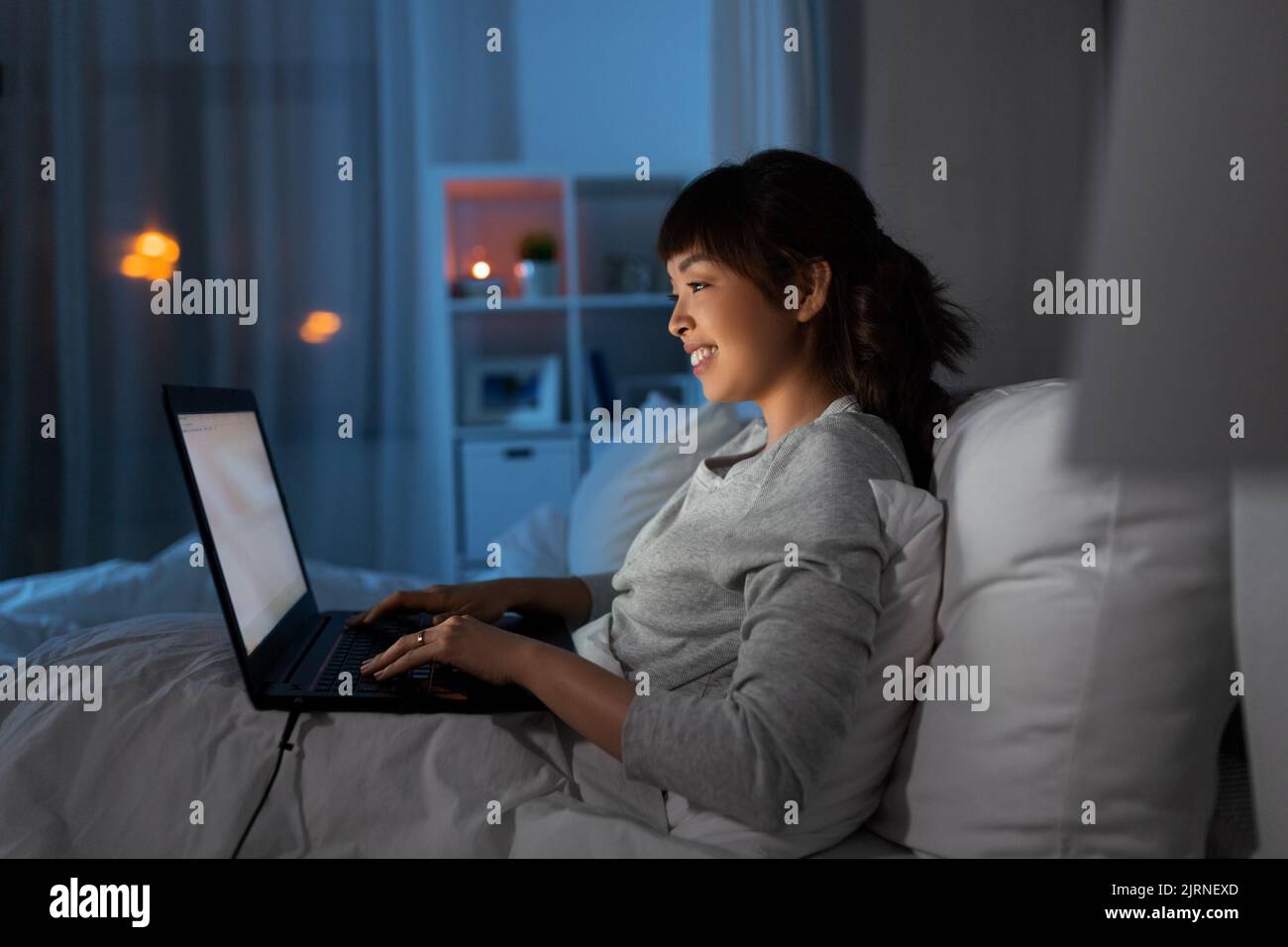 woman with laptop in bed at home at night Stock Photo - Alamy