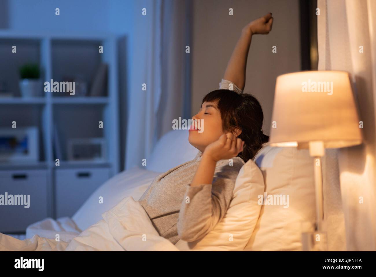 tired asian woman stretching in bed at night Stock Photo - Alamy