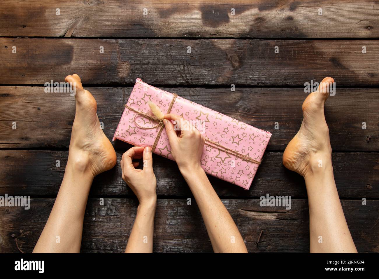 girl unfolds a birthday present on the wooden floor of the house ...