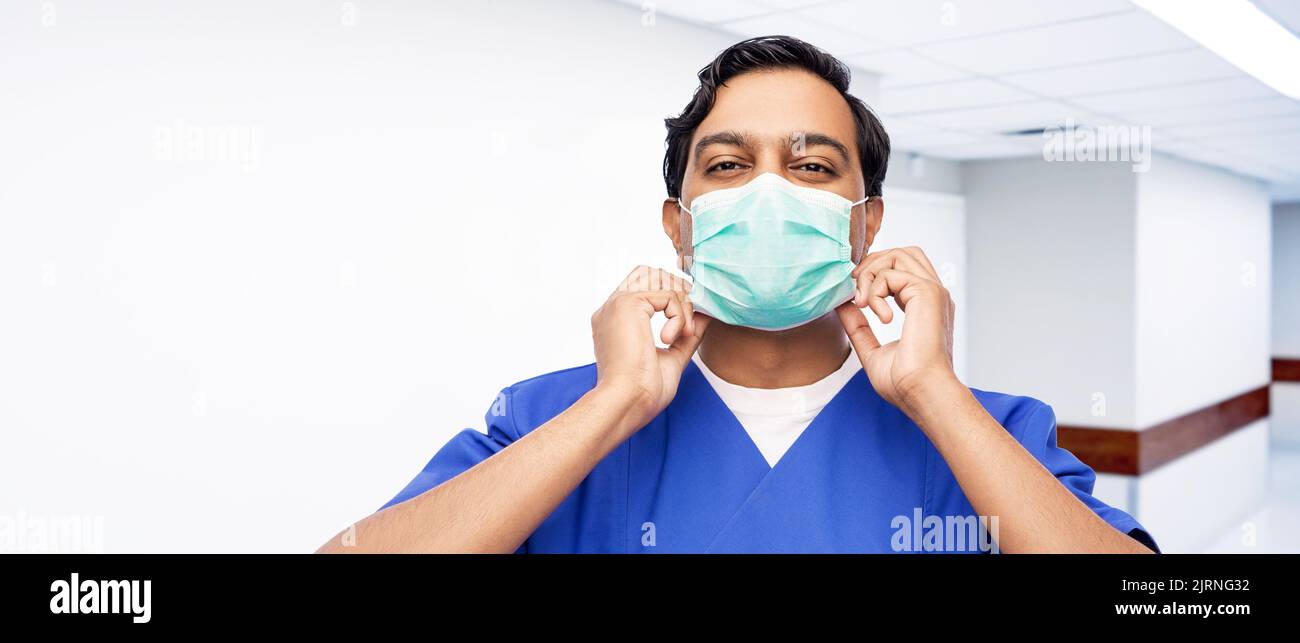 indian male doctor in blue uniform putting mask on Stock Photo - Alamy
