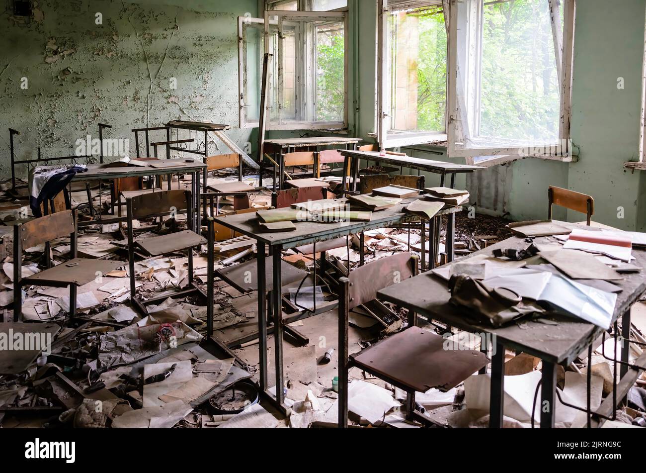 Disintegrating and vandalized classroom in Prypiat. Desks and seats are ...