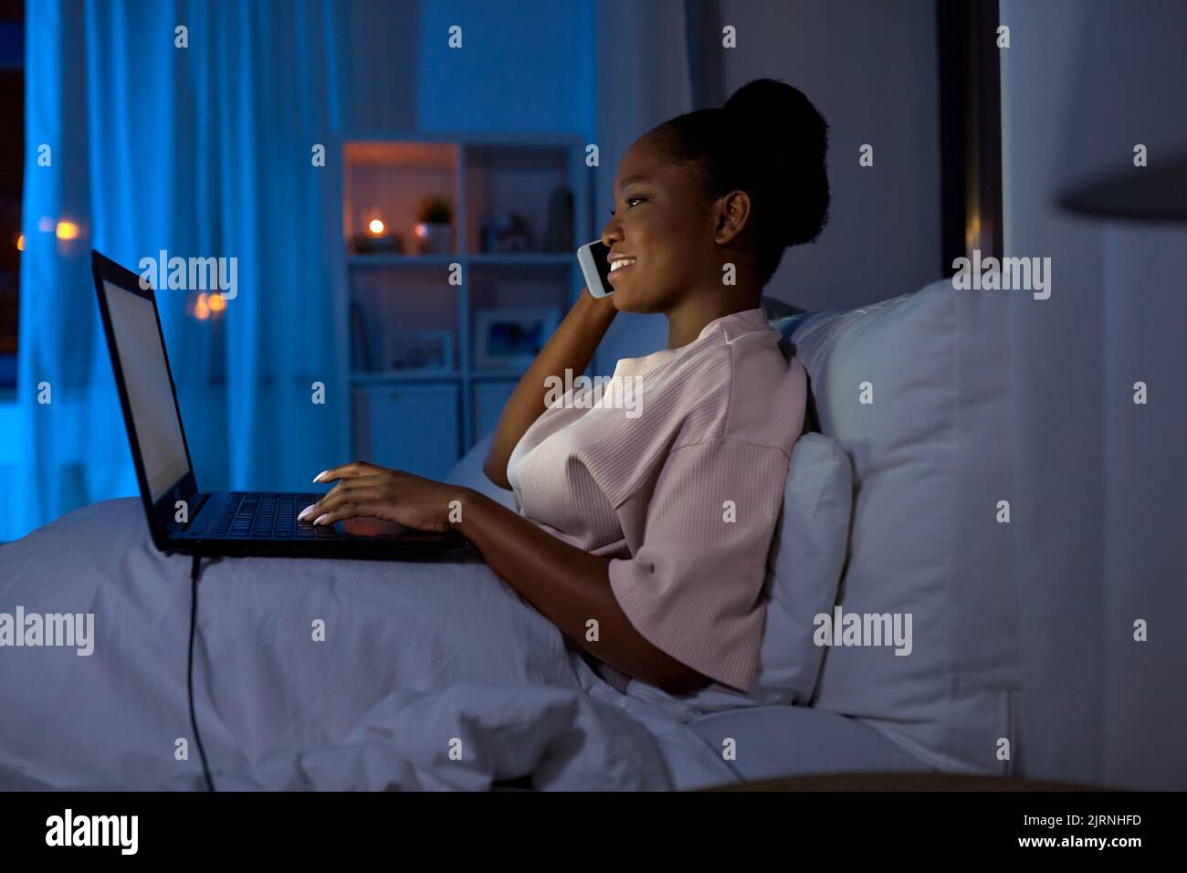 woman with laptop calling on phone in bed at night Stock Photo - Alamy