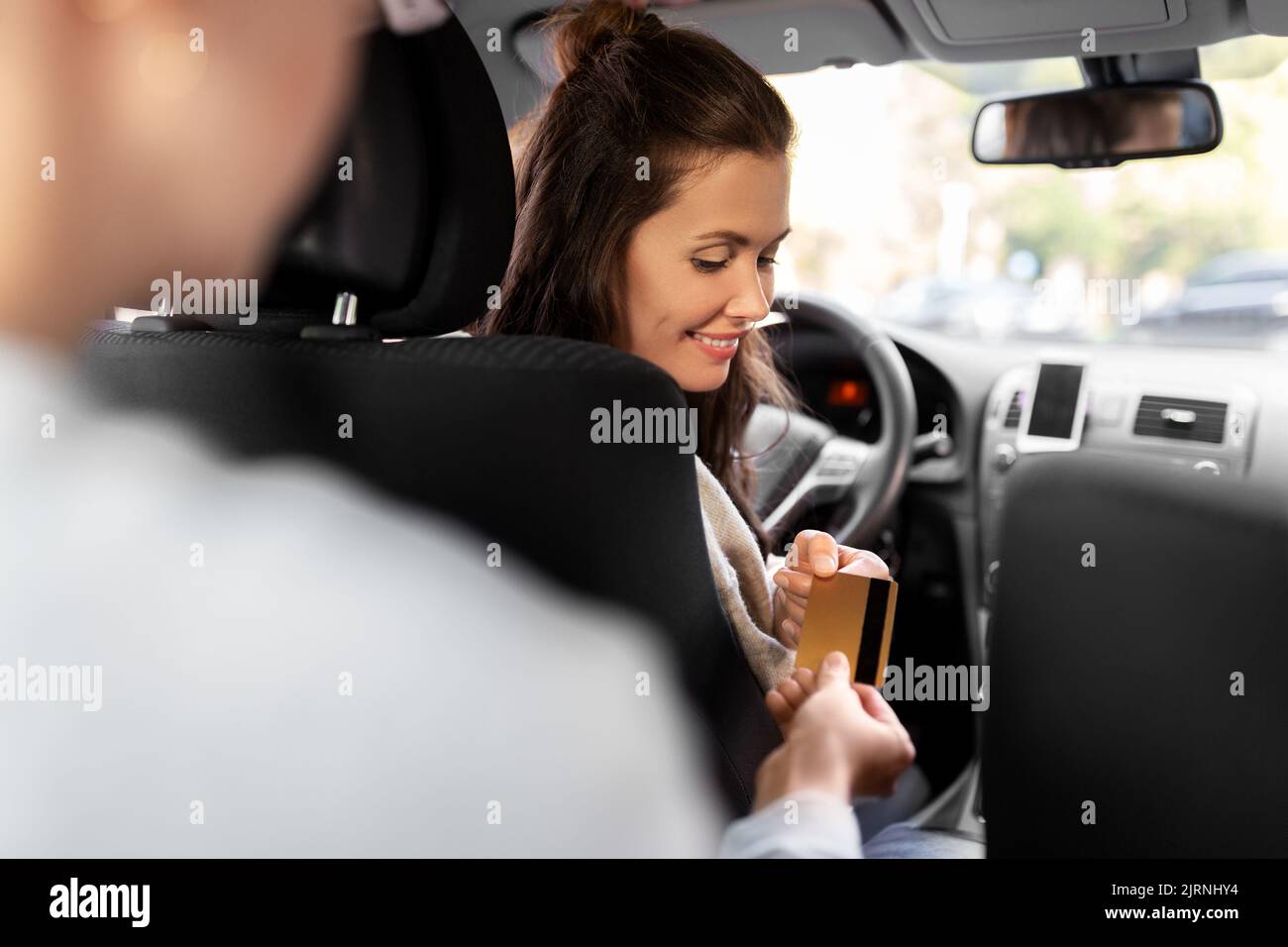 female car driver takes credit card from passenger Stock Photo - Alamy