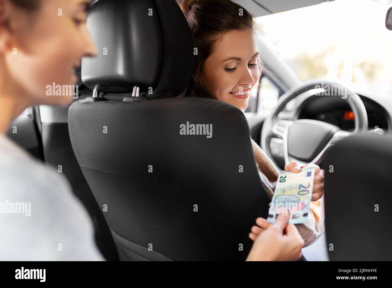 female car driver taking money from passenger Stock Photo - Alamy