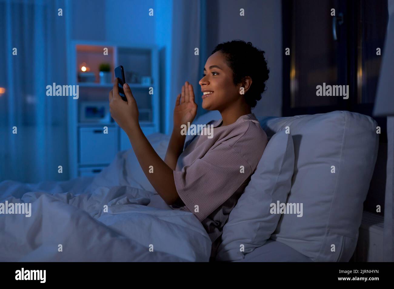 woman with phone having video call in bed at night Stock Photo - Alamy