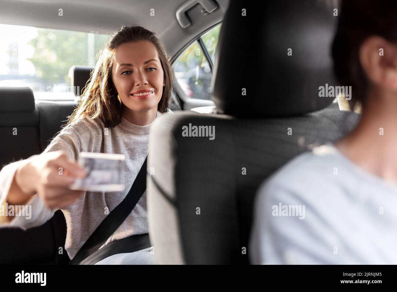 female passenger giving money to taxi car driver Stock Photo - Alamy