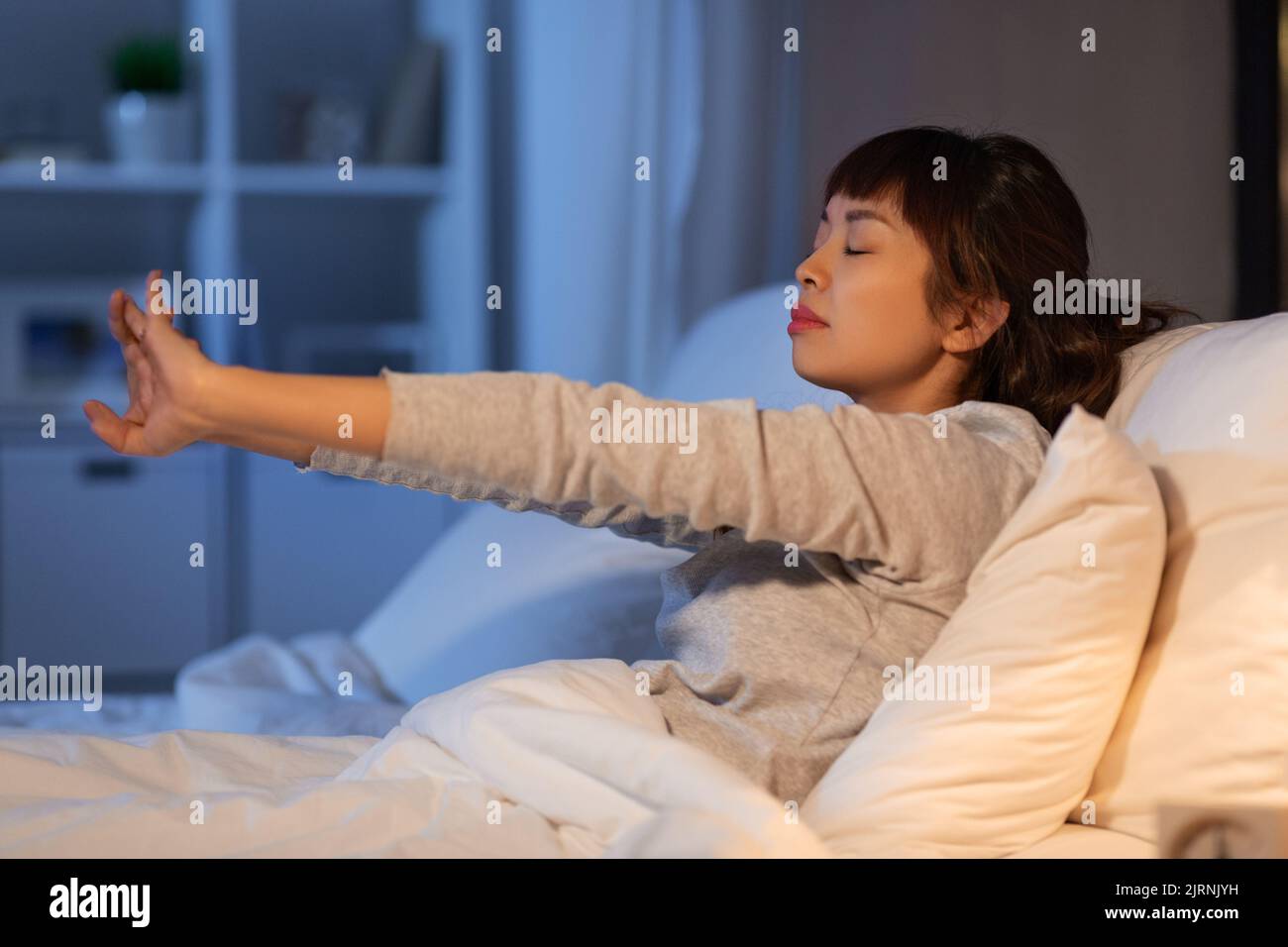 tired asian woman stretching in bed at night Stock Photo - Alamy
