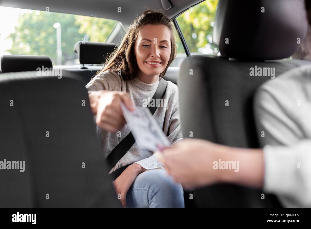 female passenger giving money to taxi car driver Stock Photo - Alamy