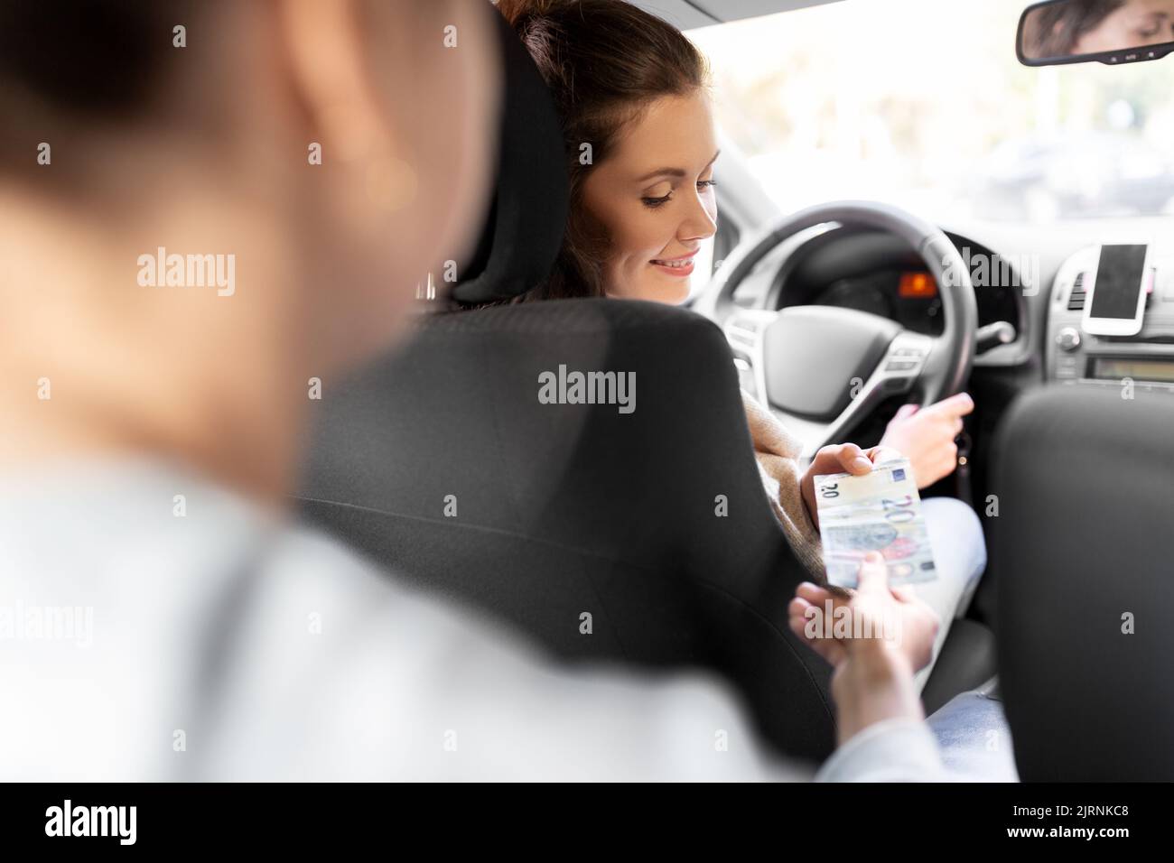 female car driver taking money from passenger Stock Photo - Alamy