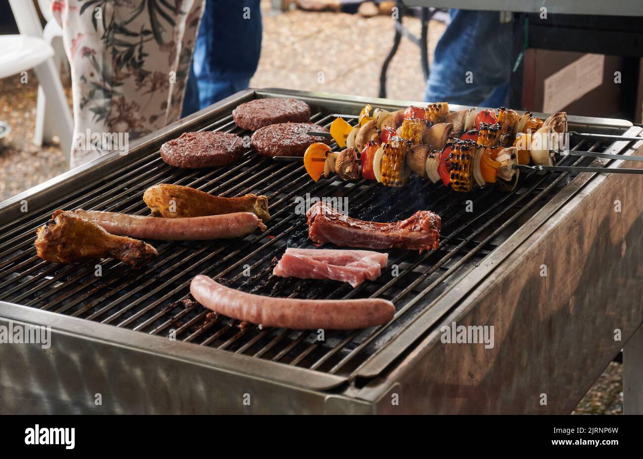 A group of people around a barbeque stand with food all over it Stock ...