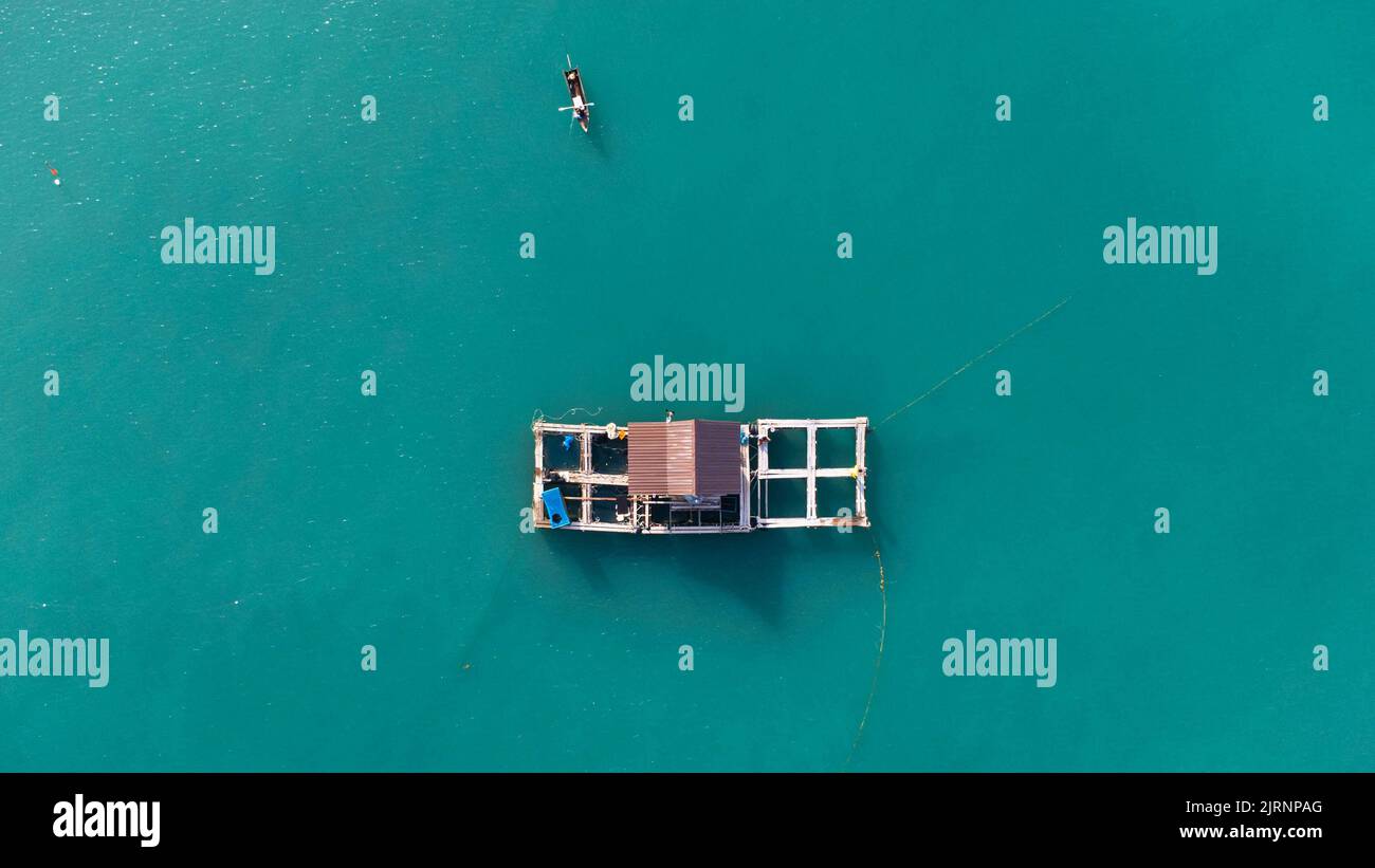 Aerial view of the fish cages and a small fishing boat floating in the ...