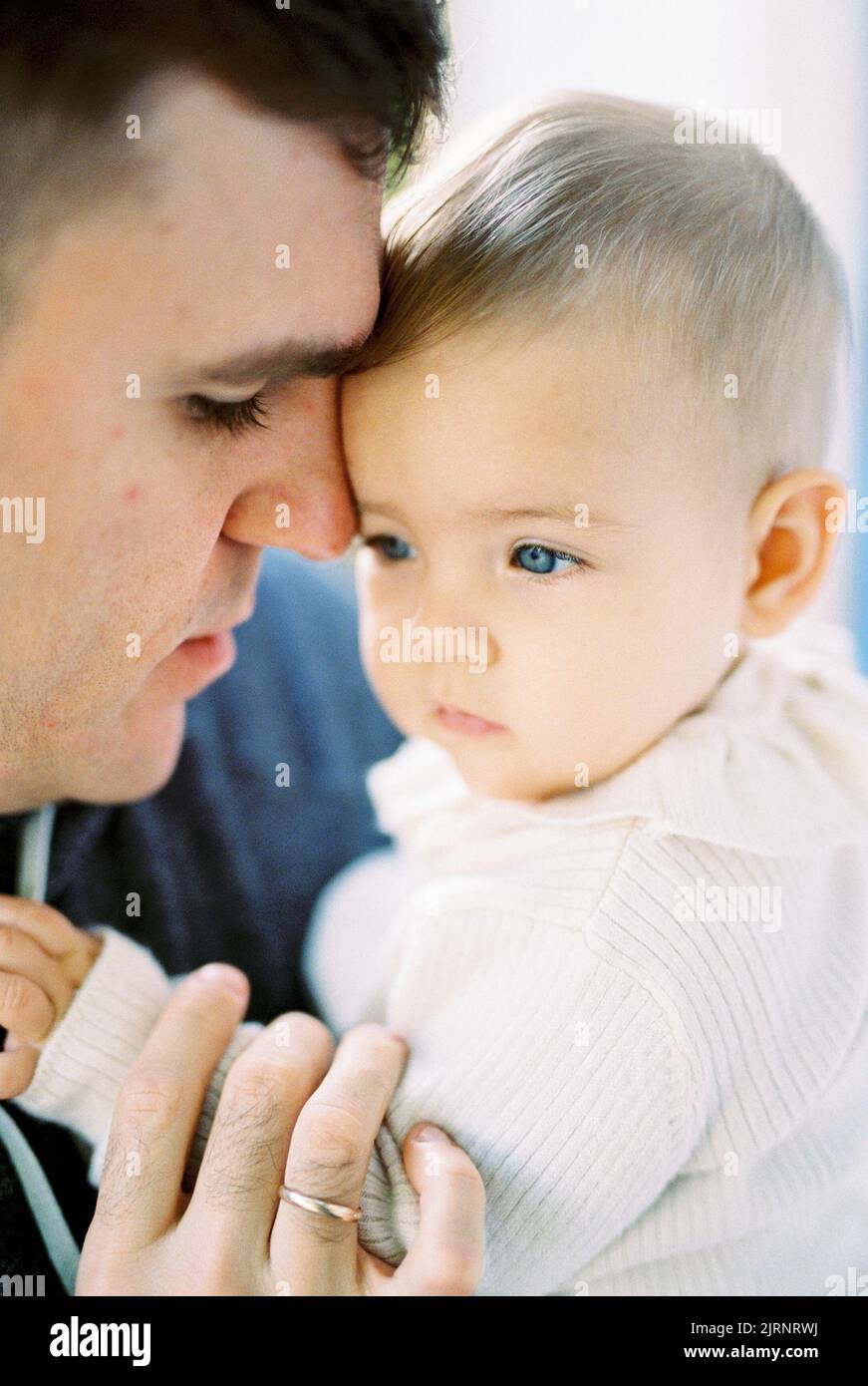Dad touches the forehead of the baby with his nose, holding his hand ...