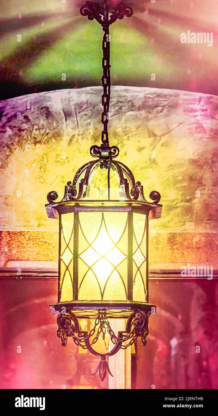 A medieval style electric lamp is illuminated inside of an old building ...