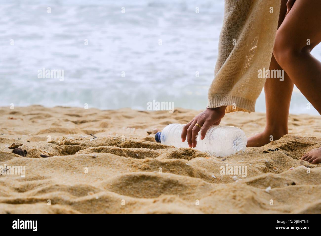 Woman cleaning plastic on the beach. People voluntarily clean nature ...