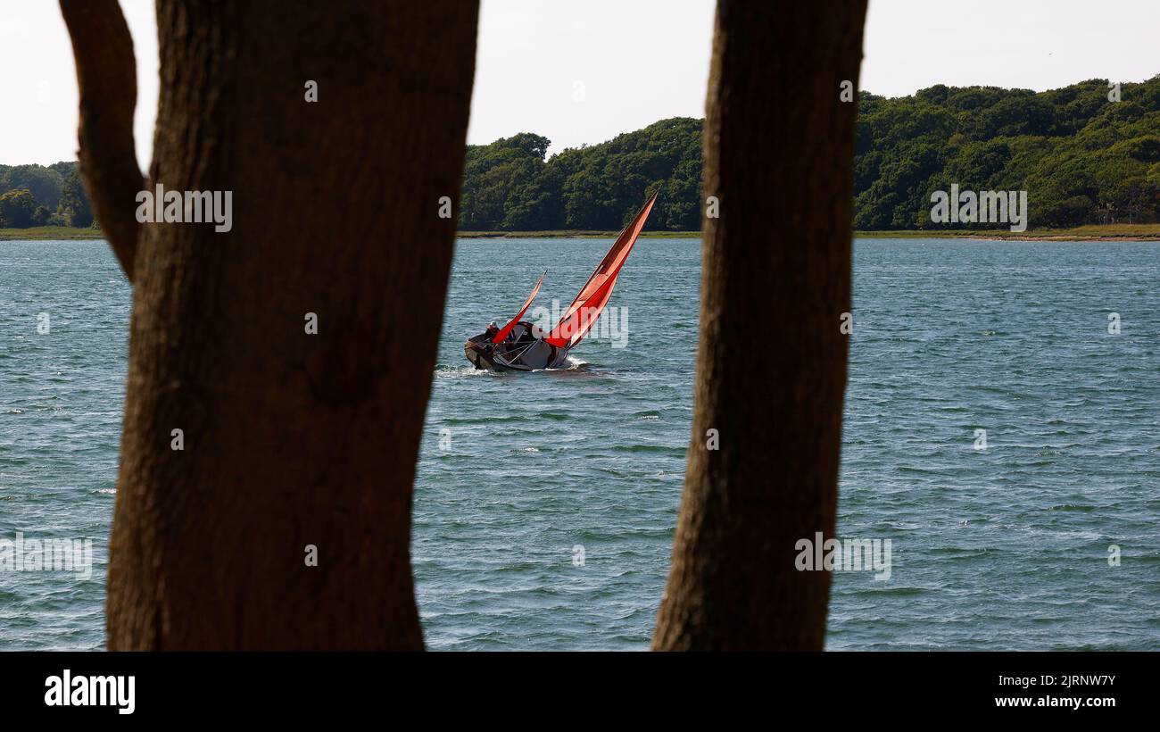 Tilting sailing boat seen heeling over on choppy waters being framed by ...