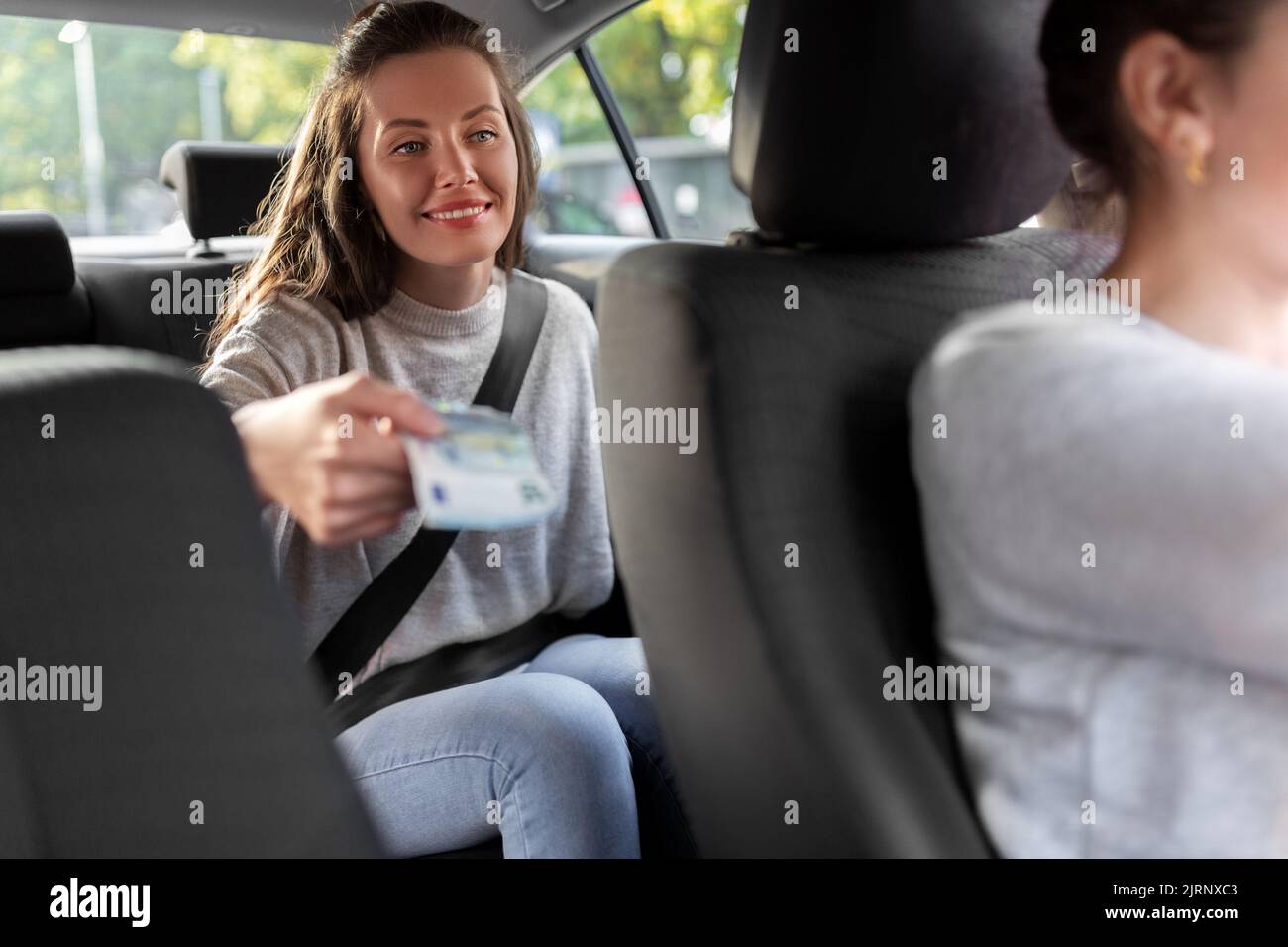 female passenger giving money to taxi car driver Stock Photo - Alamy