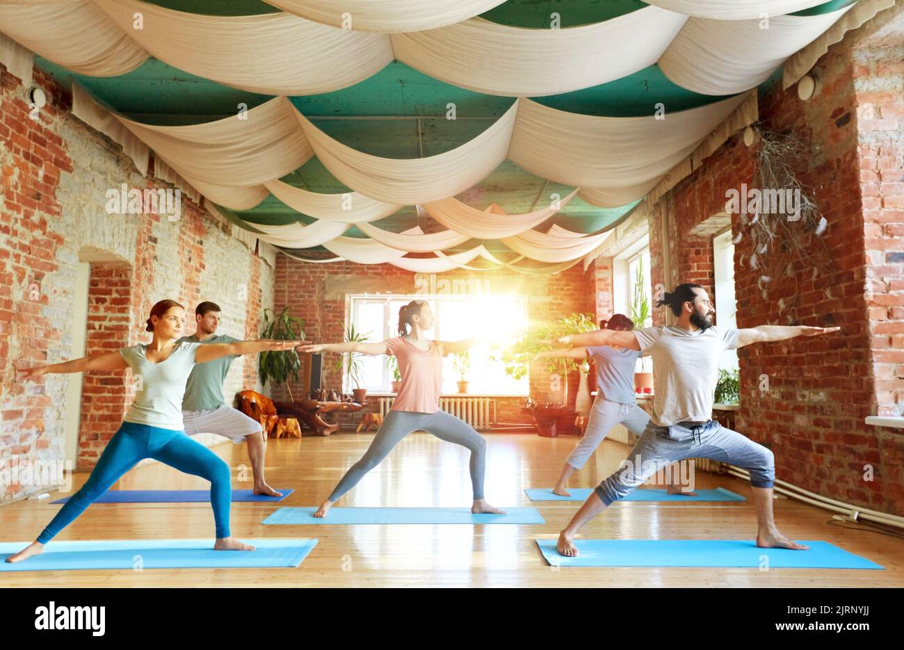 group of people doing yoga warrior pose at studio Stock Photo - Alamy