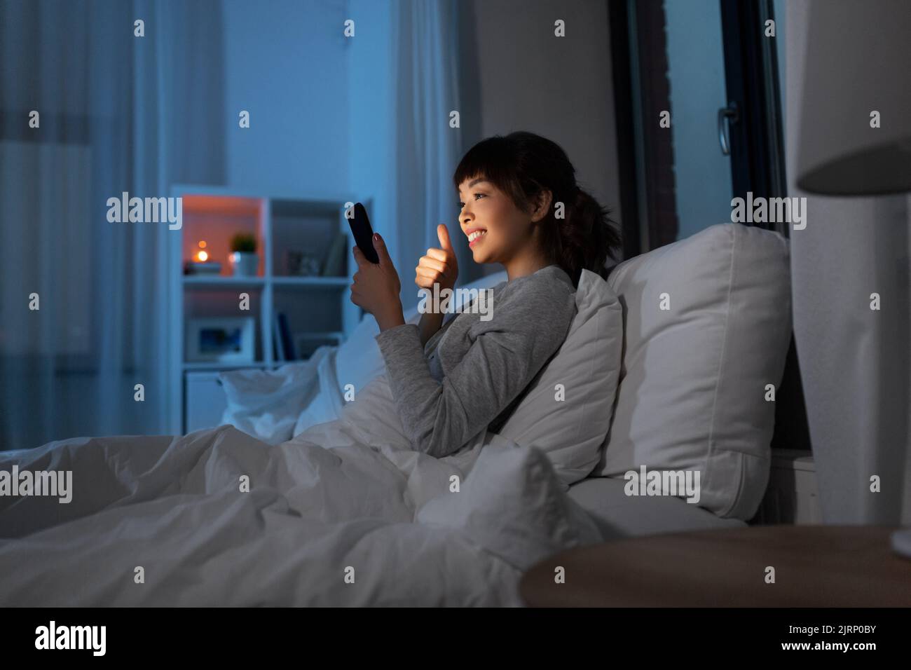 woman with phone having video call in bed at night Stock Photo - Alamy