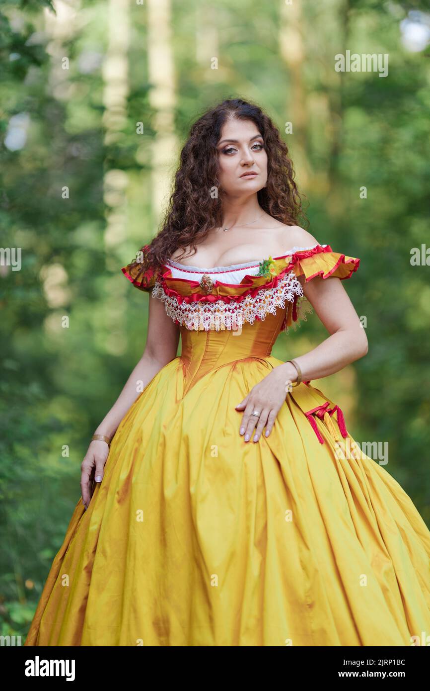 A young woman in an ancient medieval yellow orange dress walks in a ...