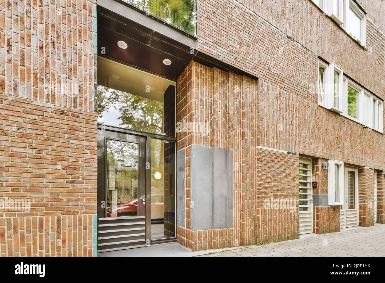 The front view of a brick building with signs,pavement and wooden doors ...
