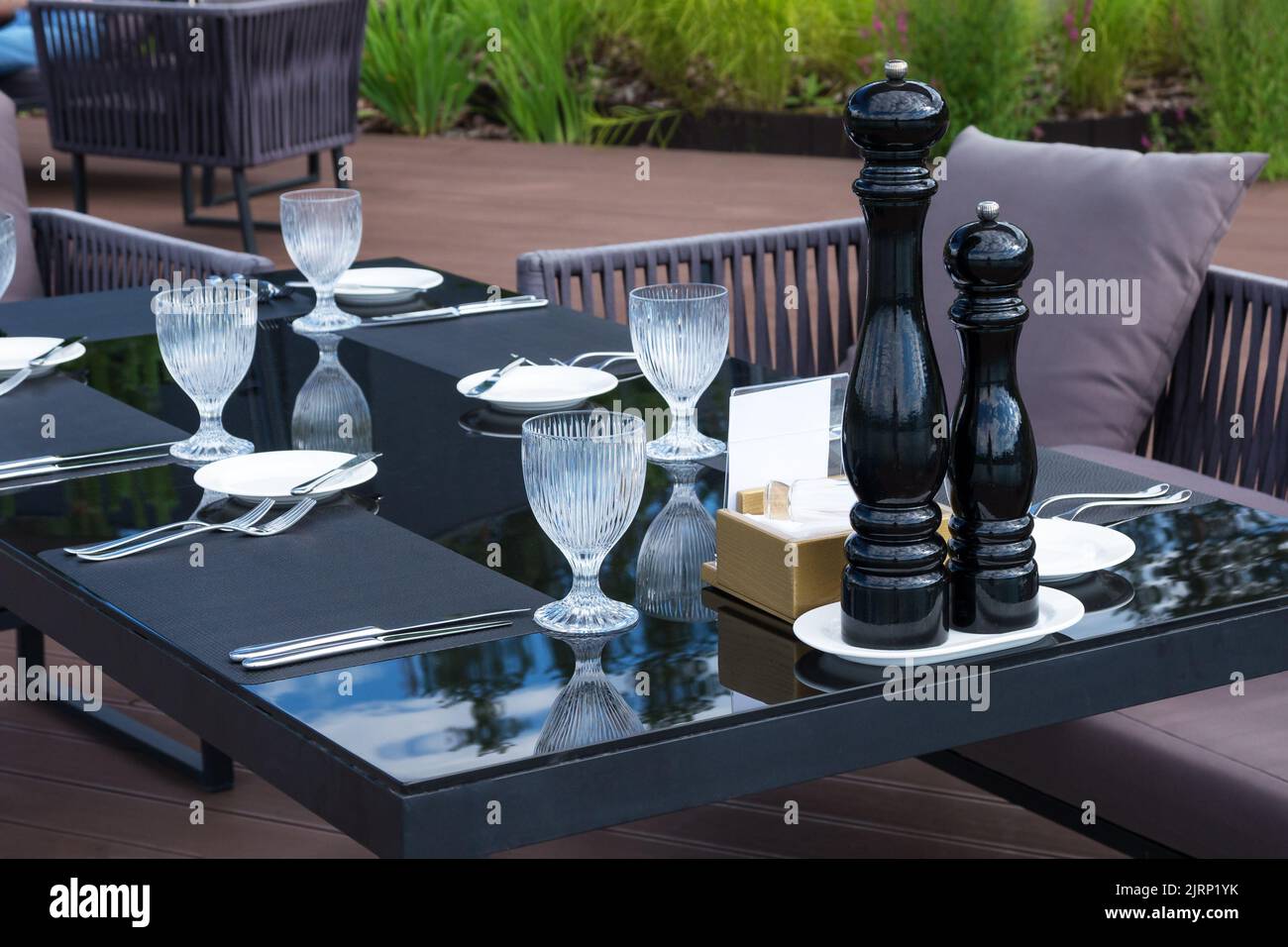 Crystal empty glasses, white plates and cutlery on a table in a beach ...