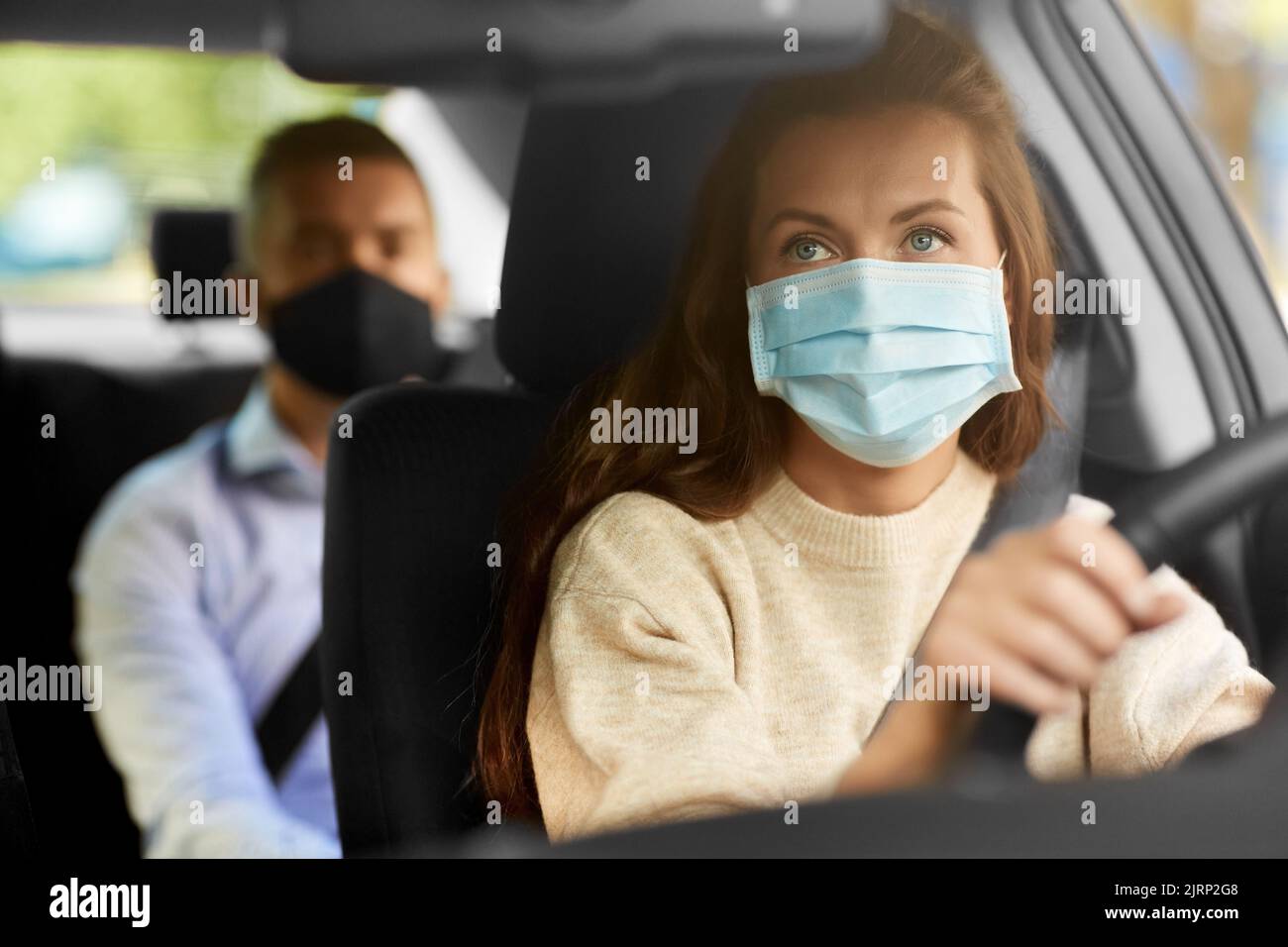 female driver in mask driving car with passenger Stock Photo - Alamy