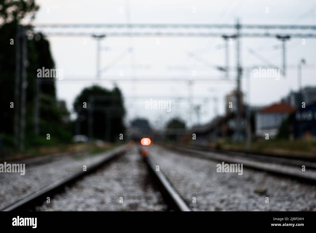 A blurred grey shot of a railway with train lights in the distance ...