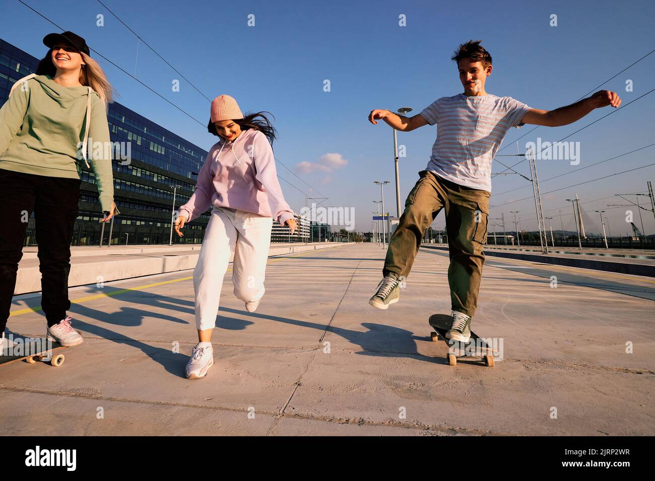 Three excited teenagers spend time in the urban exterior. They are ...