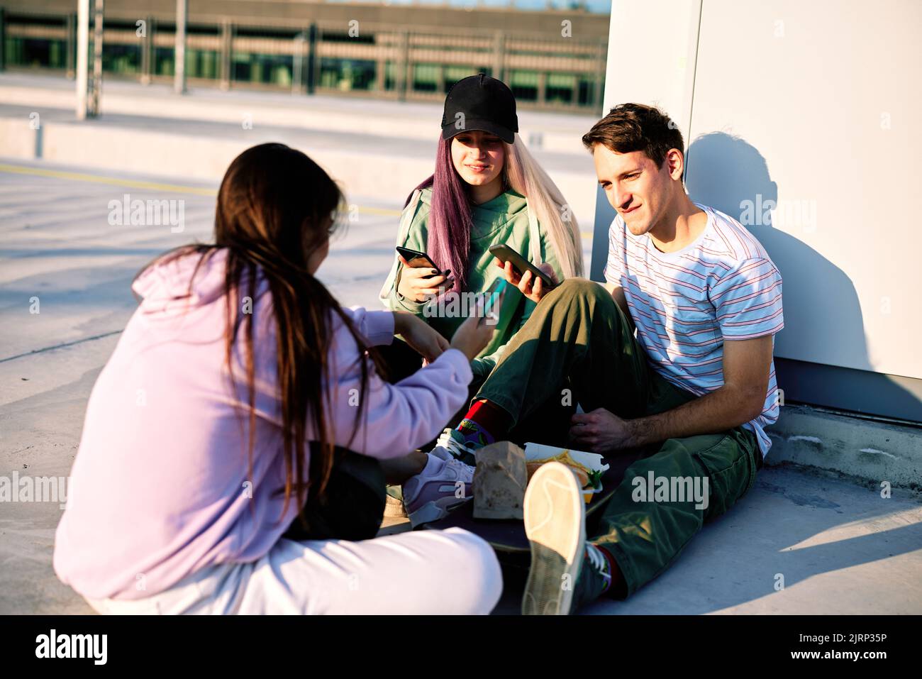 A small group of teenagers sitting outdoors in urban exterior and ...