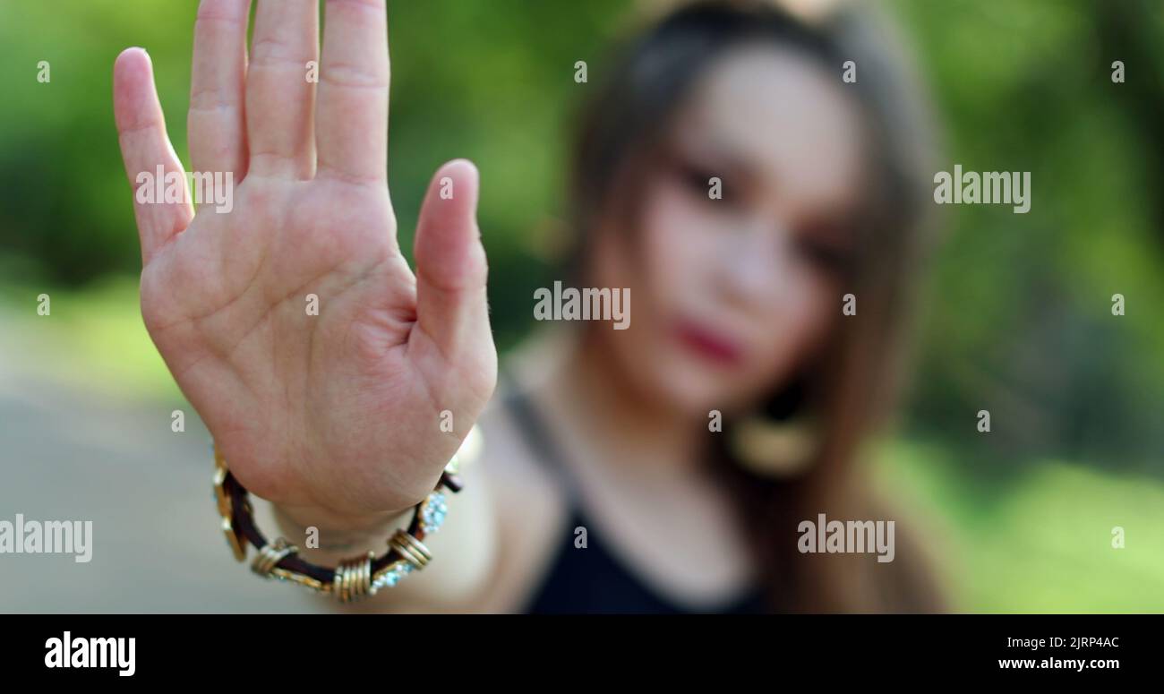 Attractive young woman blocking with hand and gesturing NO with finger ...